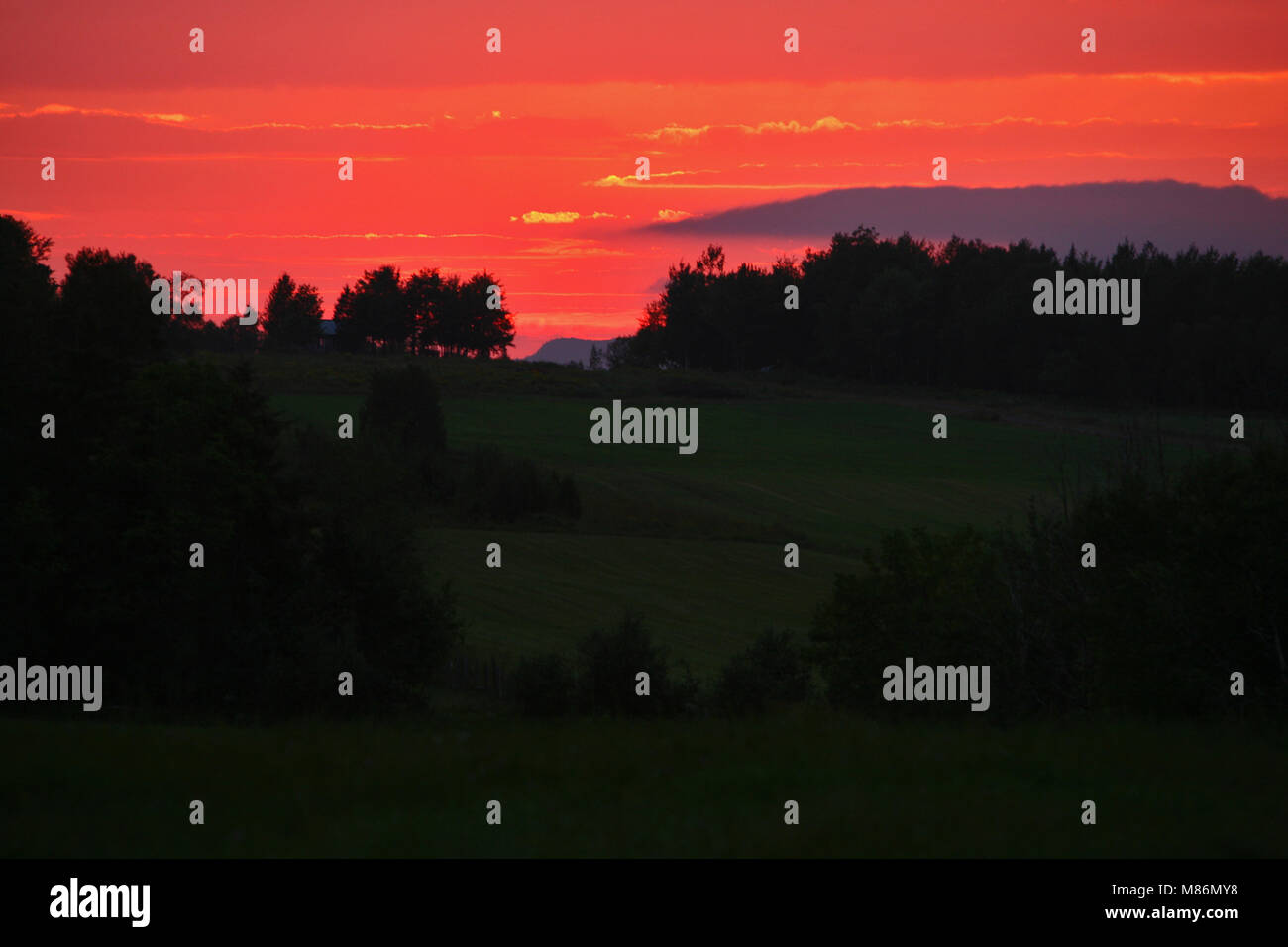 bright pink sunset lighting up the clouds with green fields Stock Photo ...