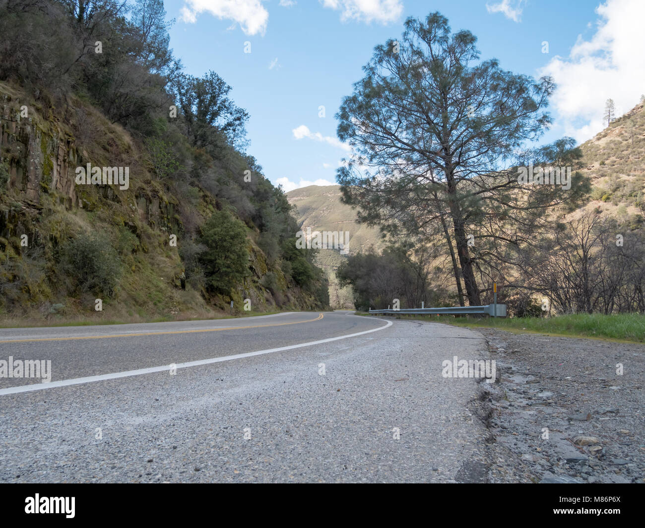 Low Angle View of Road That Curves Right With Large Mountains on each ...