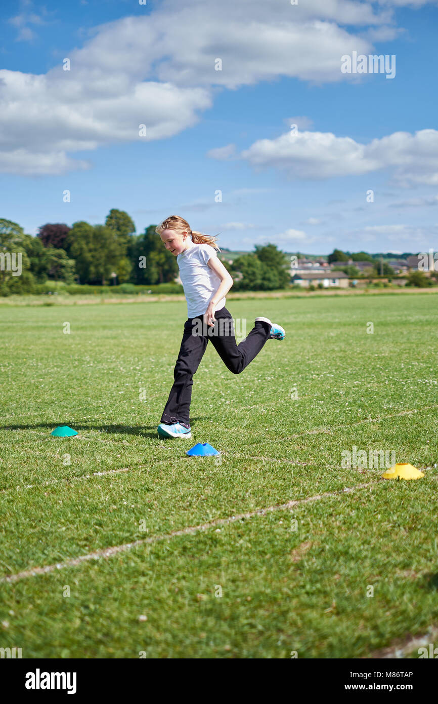 A young girl crosses the finish line in a running event on a grass ...