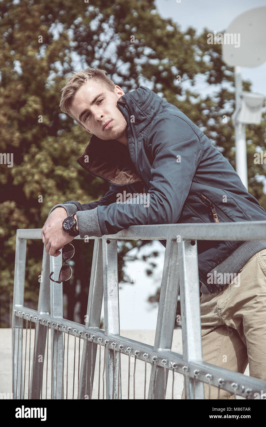 Handsome young man keeping arms crossed on the balustrade and looking ...