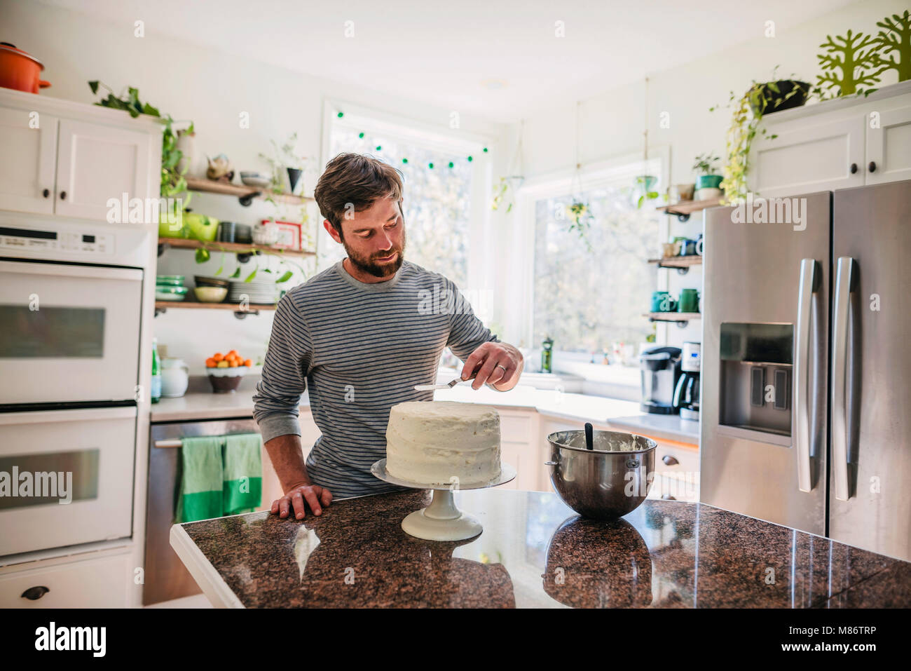 Man standing in the kitchen decorating a cake Stock Photo - Alamy