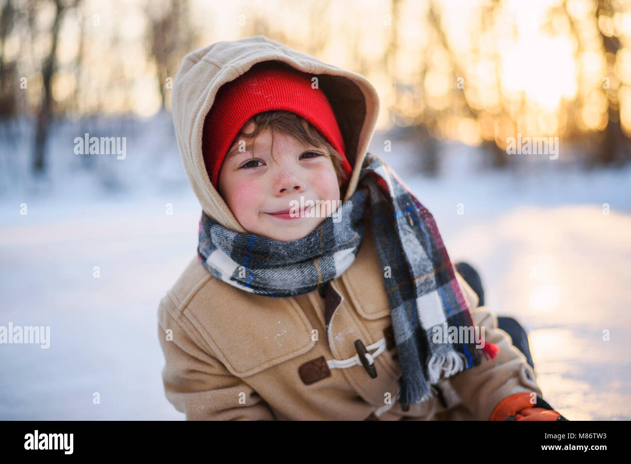 Portrait of a smiling boy sitting on frozen lake Stock Photo - Alamy