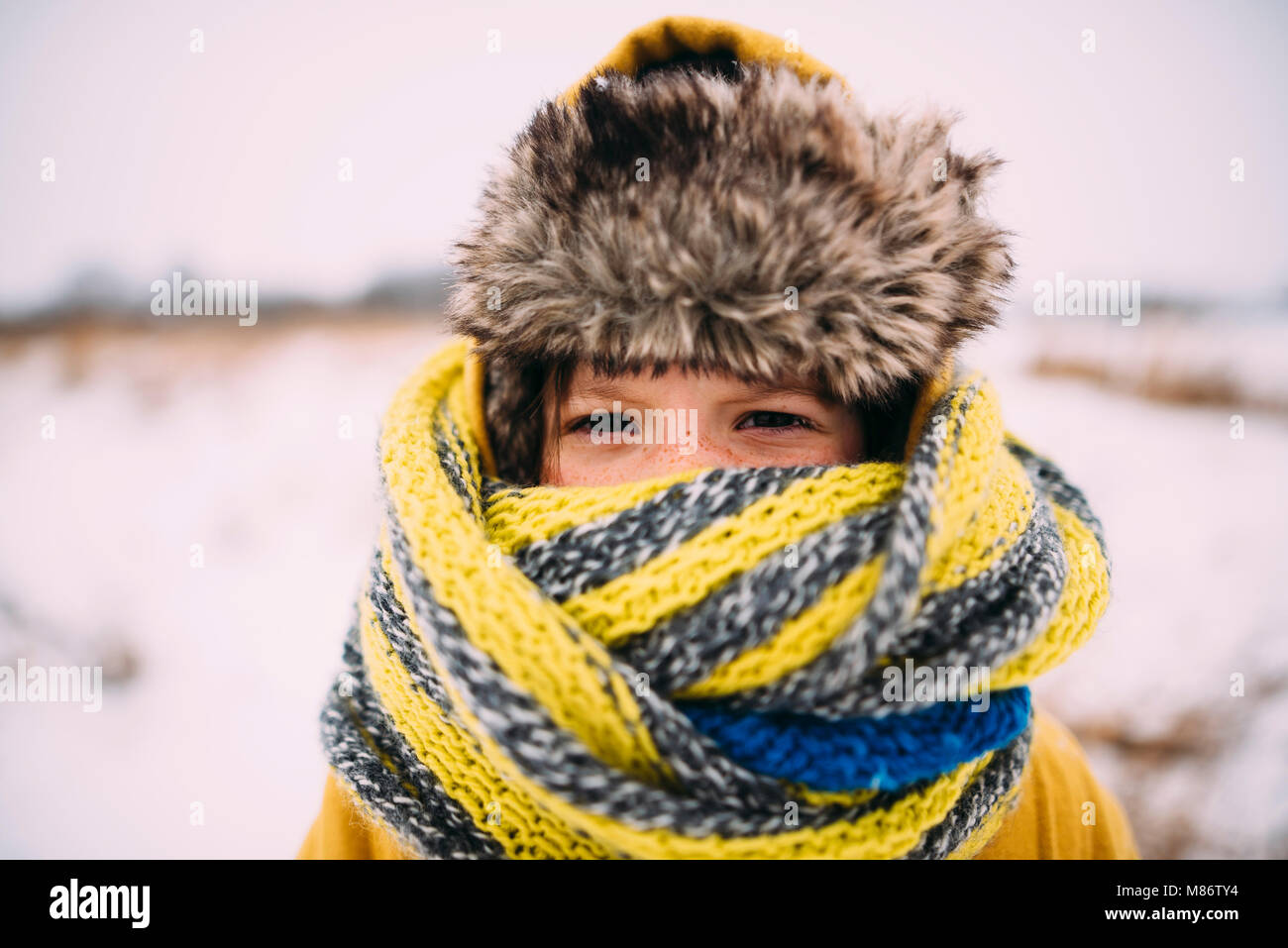 Portrait of a girl standing in the snow wrapped up in a hat and scarf ...