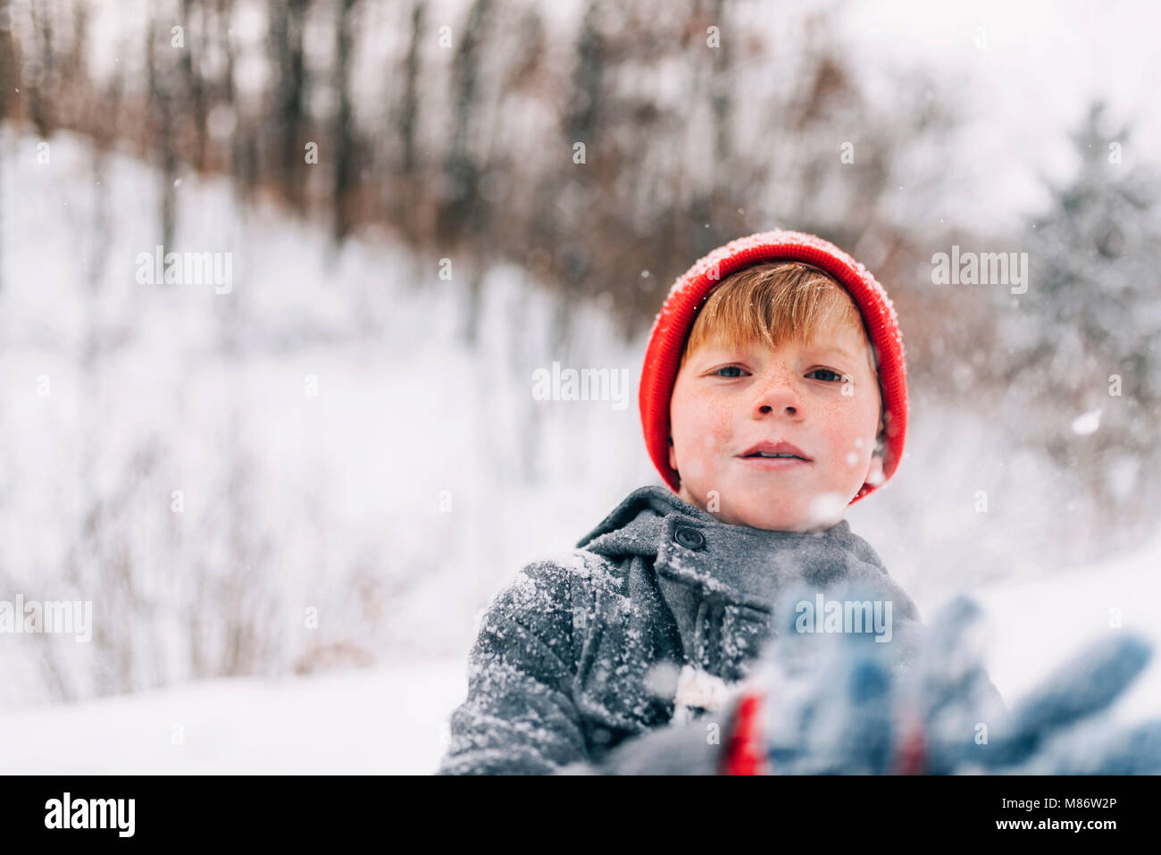 Boy standing outdoors throwing snow Stock Photo - Alamy