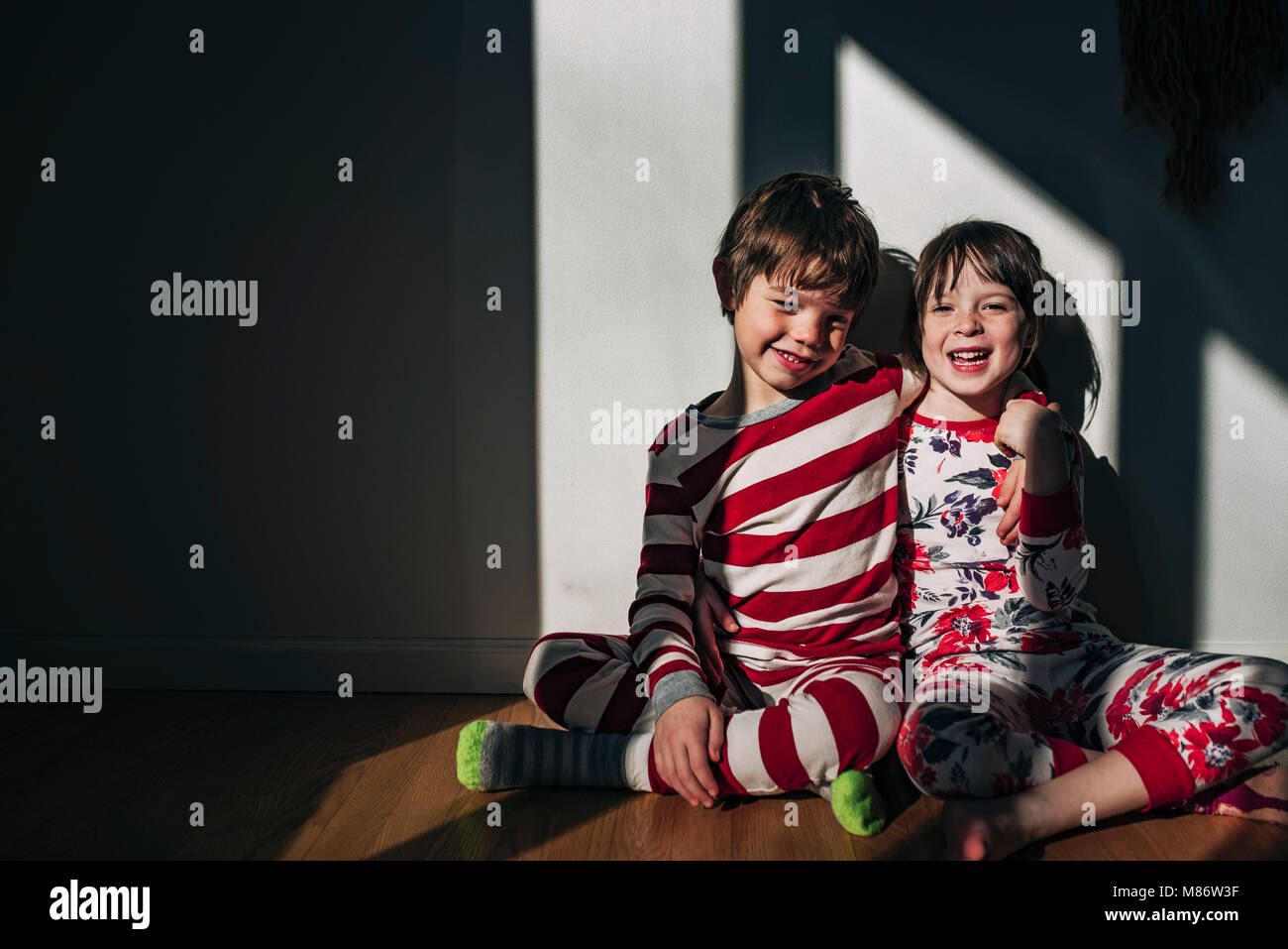 Boy and girl sitting on floor hugging Stock Photo - Alamy