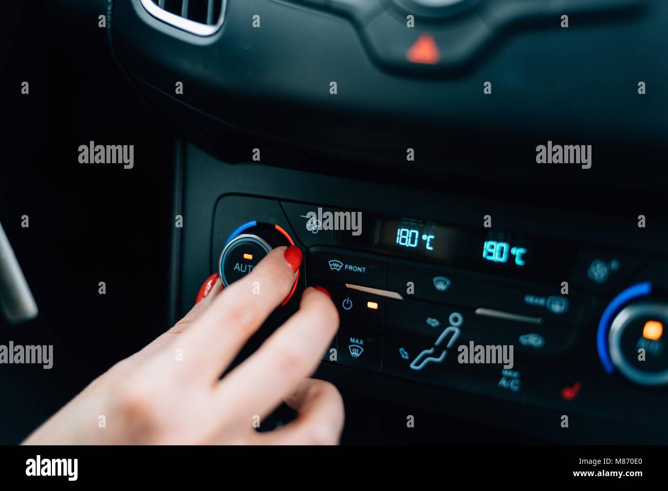 Woman regulating temperature on car air condition. Modern car interior ...
