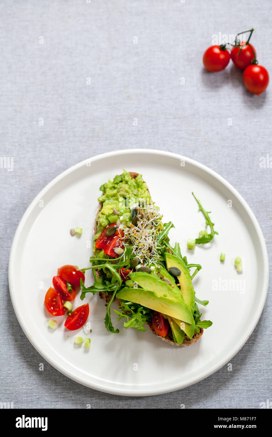 Rye toast with avocado, tomatoes and alfalfa sprouts Stock Photo - Alamy