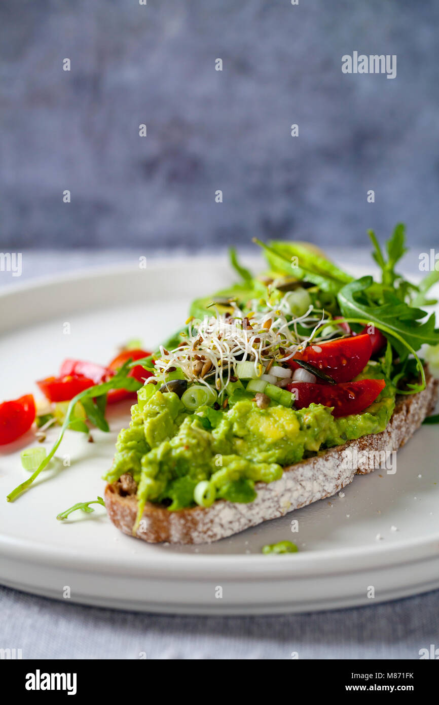Rye toast with avocado, tomatoes and alfalfa sprouts Stock Photo - Alamy