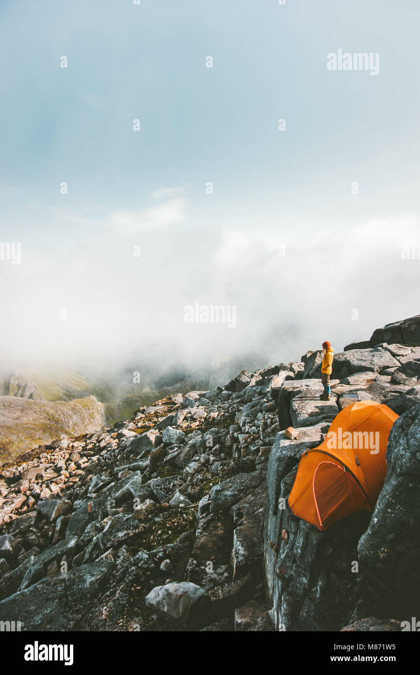 Camping tent on the top of mountain rocky cliff and traveler enjoying ...