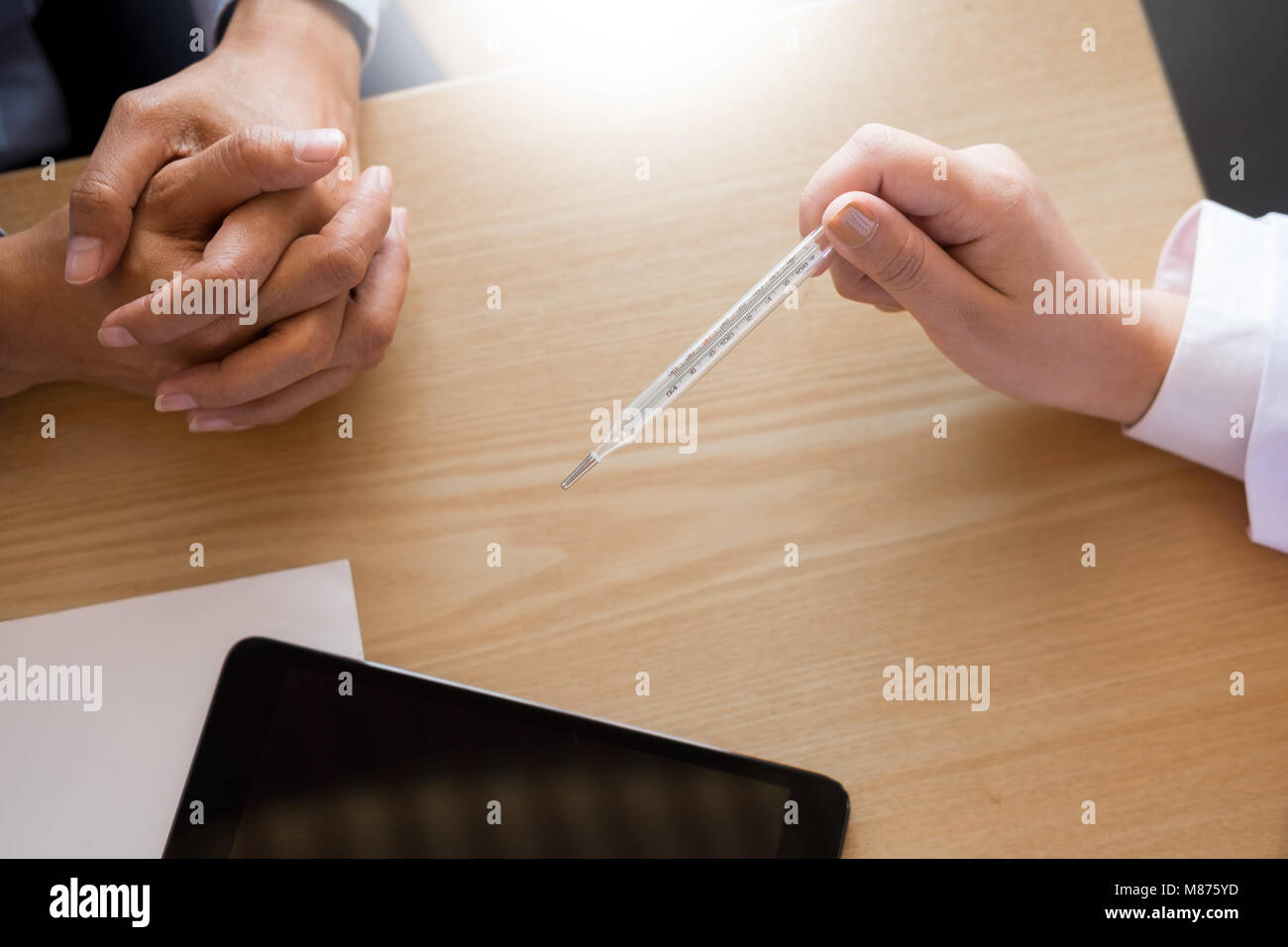 Doctor with a thermometer in his hand taking patient's in hospital ...