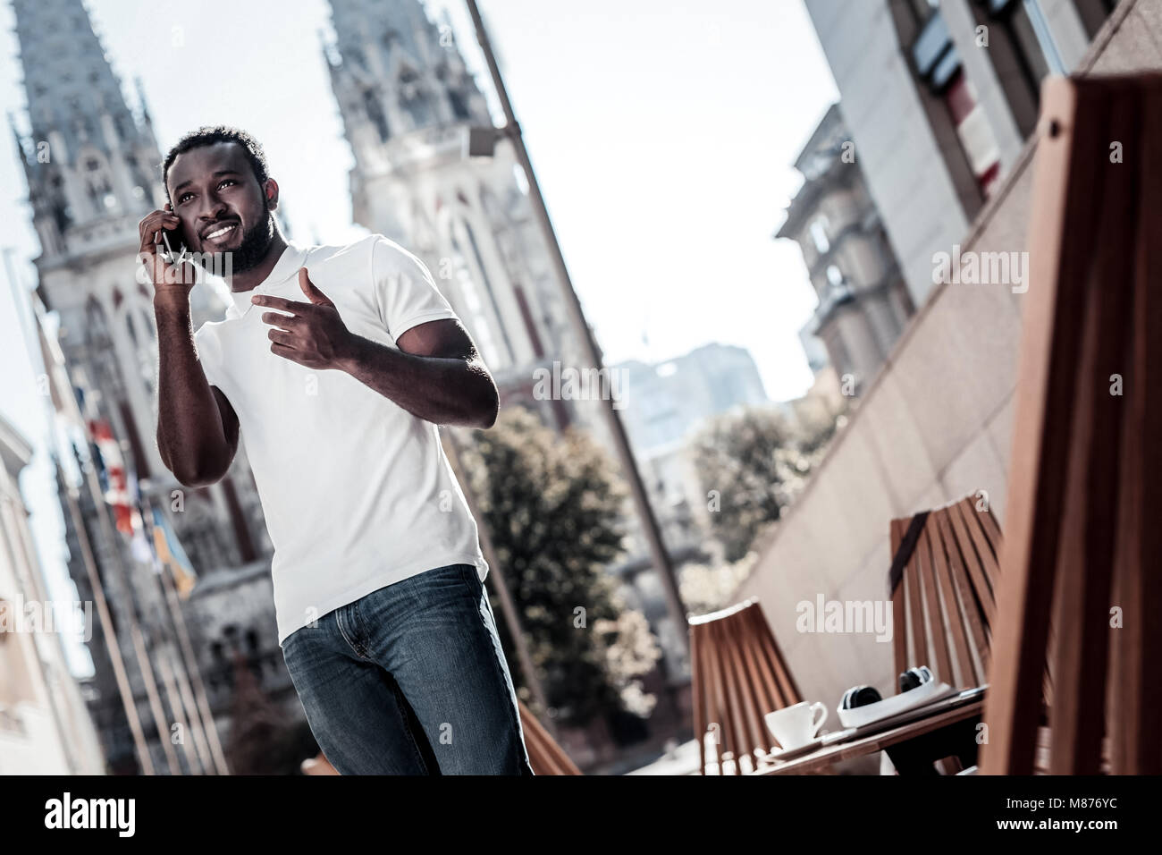 Friendly looking young man enjoying pleasant conversation on phone ...