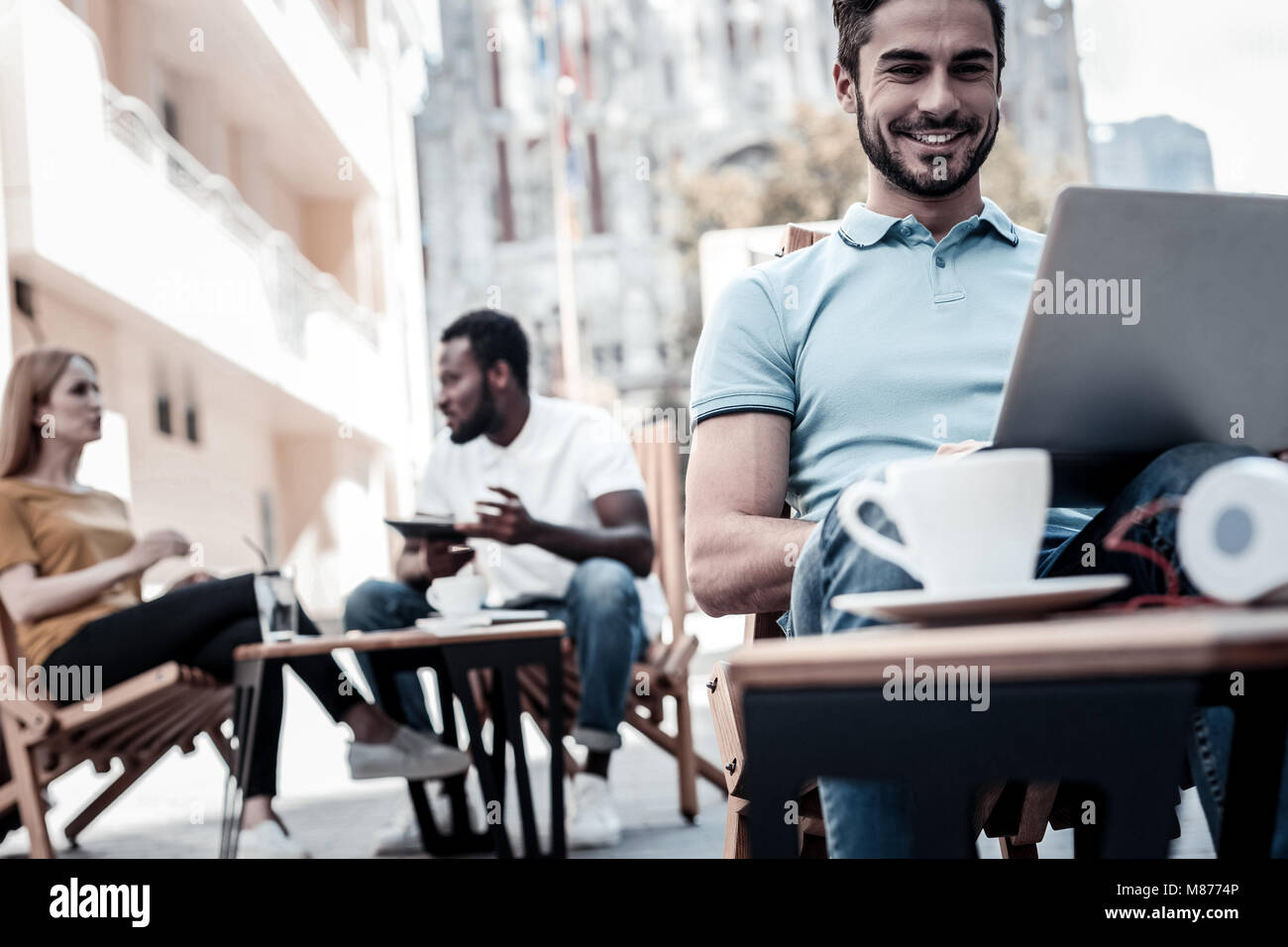 Cheerful young man smiling while working on laptop Stock Photo - Alamy