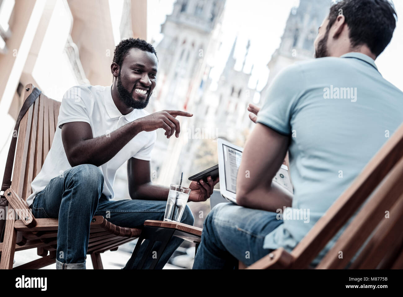 Radiant millennial people smiling while talking outdoors Stock Photo ...