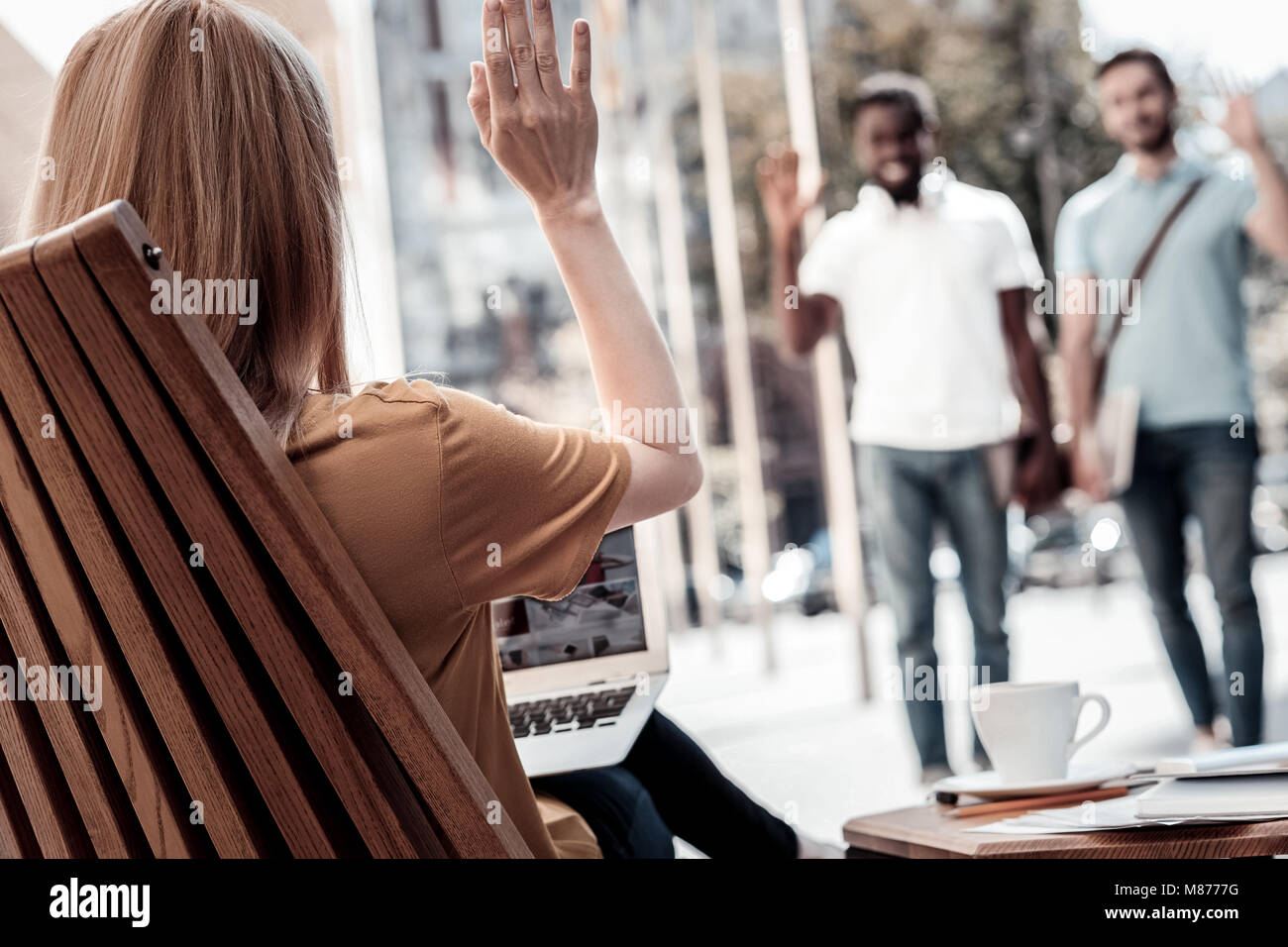 Female entrepreneur waving to her colleagues Stock Photo - Alamy