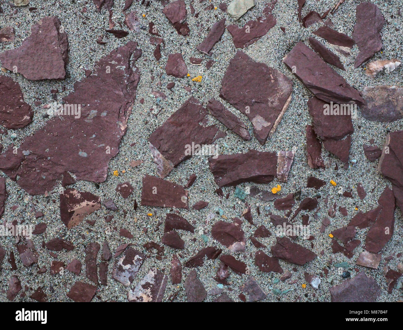 Abstract natural background from angular maroon stones in green sand ...