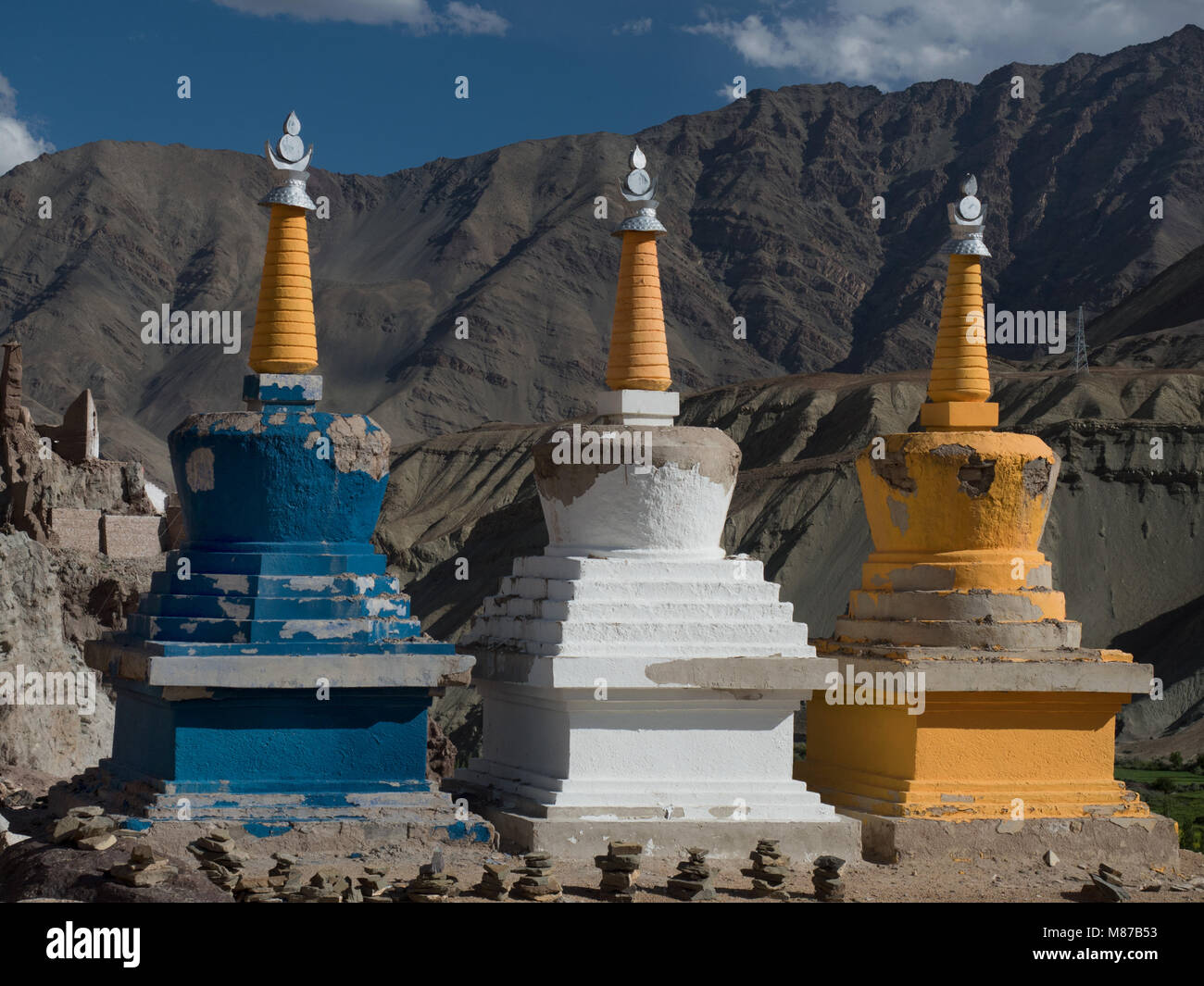 Three Buddhist stupas of blue, white and yellow with yellow spiers ...