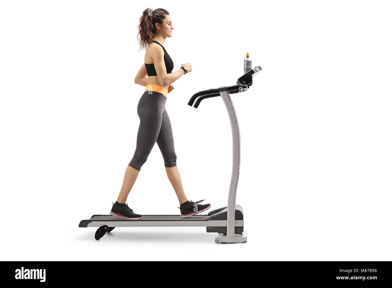 Full length profile shot of a fitness woman walking on a treadmill ...