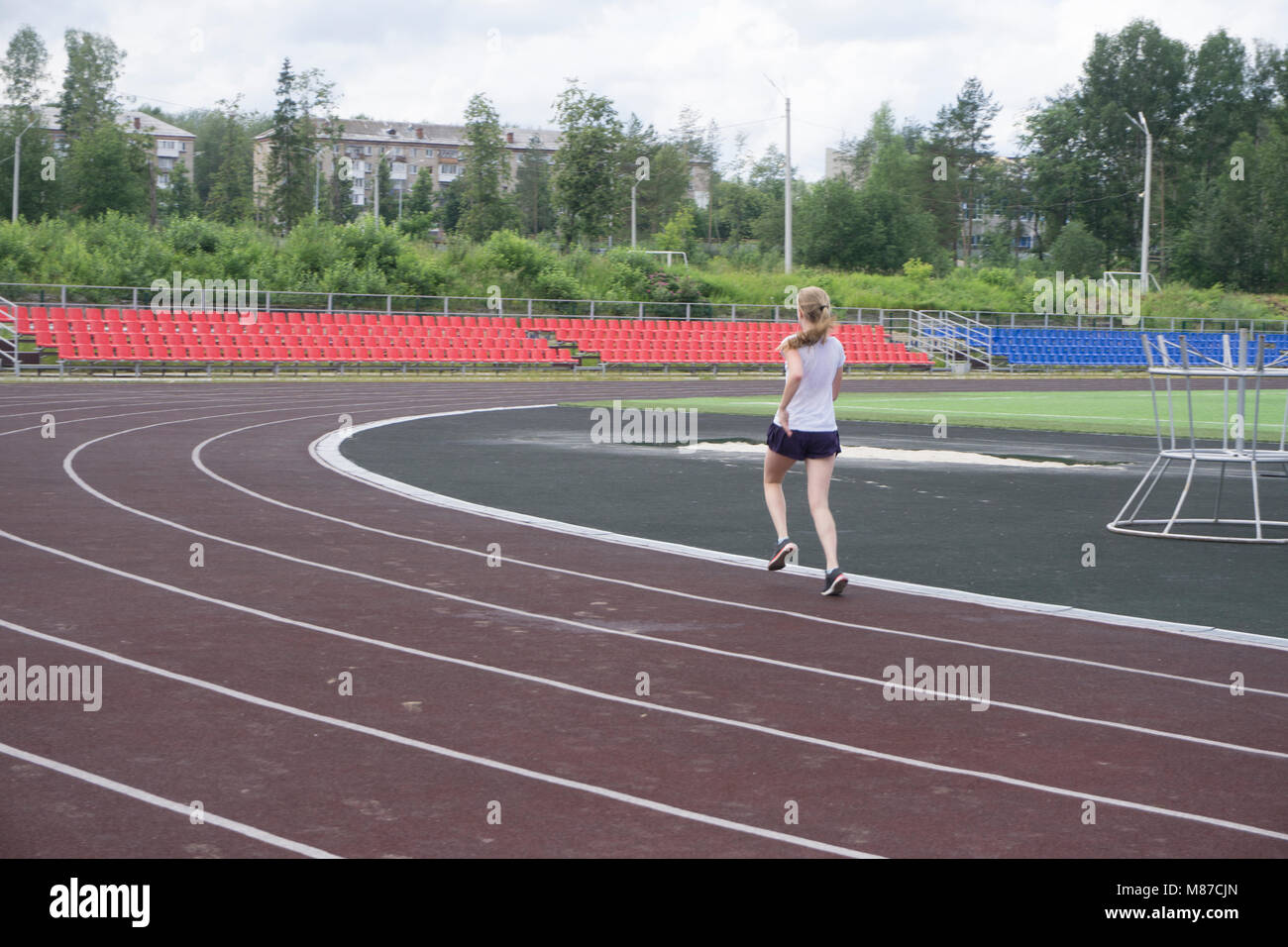 The girl is running around the stadium. Training outdoors. Back view ...