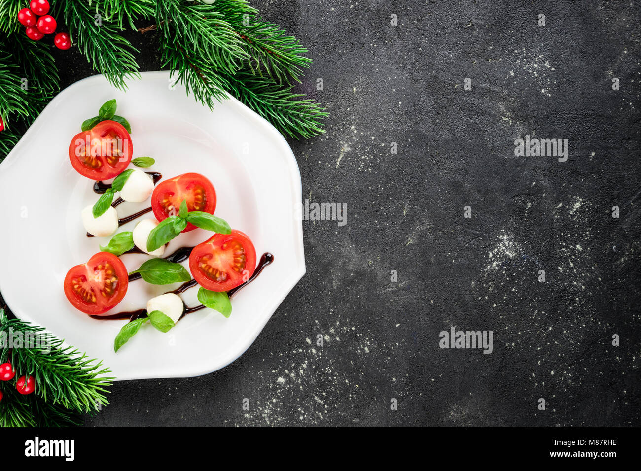 Caprese salad in the shape of christmas tree. Festive appetizer on dark ...