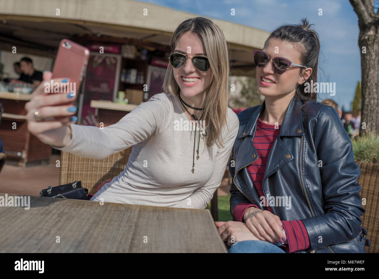 Two beautiful young women having fun outdoors while using their ...