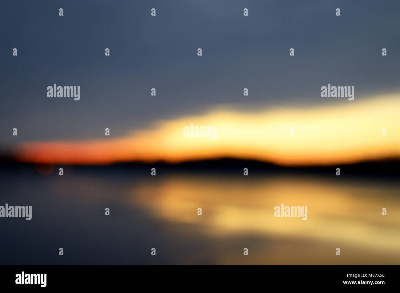 Blurred Sunset Between Cloudy Sky and Lake Stock Photo - Alamy