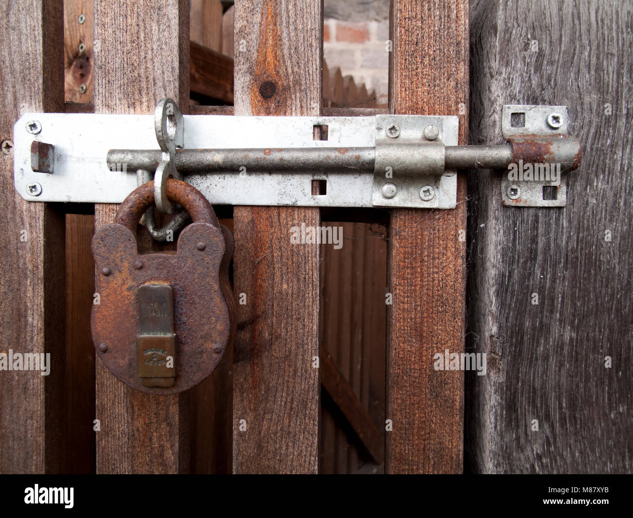 Rusty padlock clasp and staple securing timber gate to side of ...