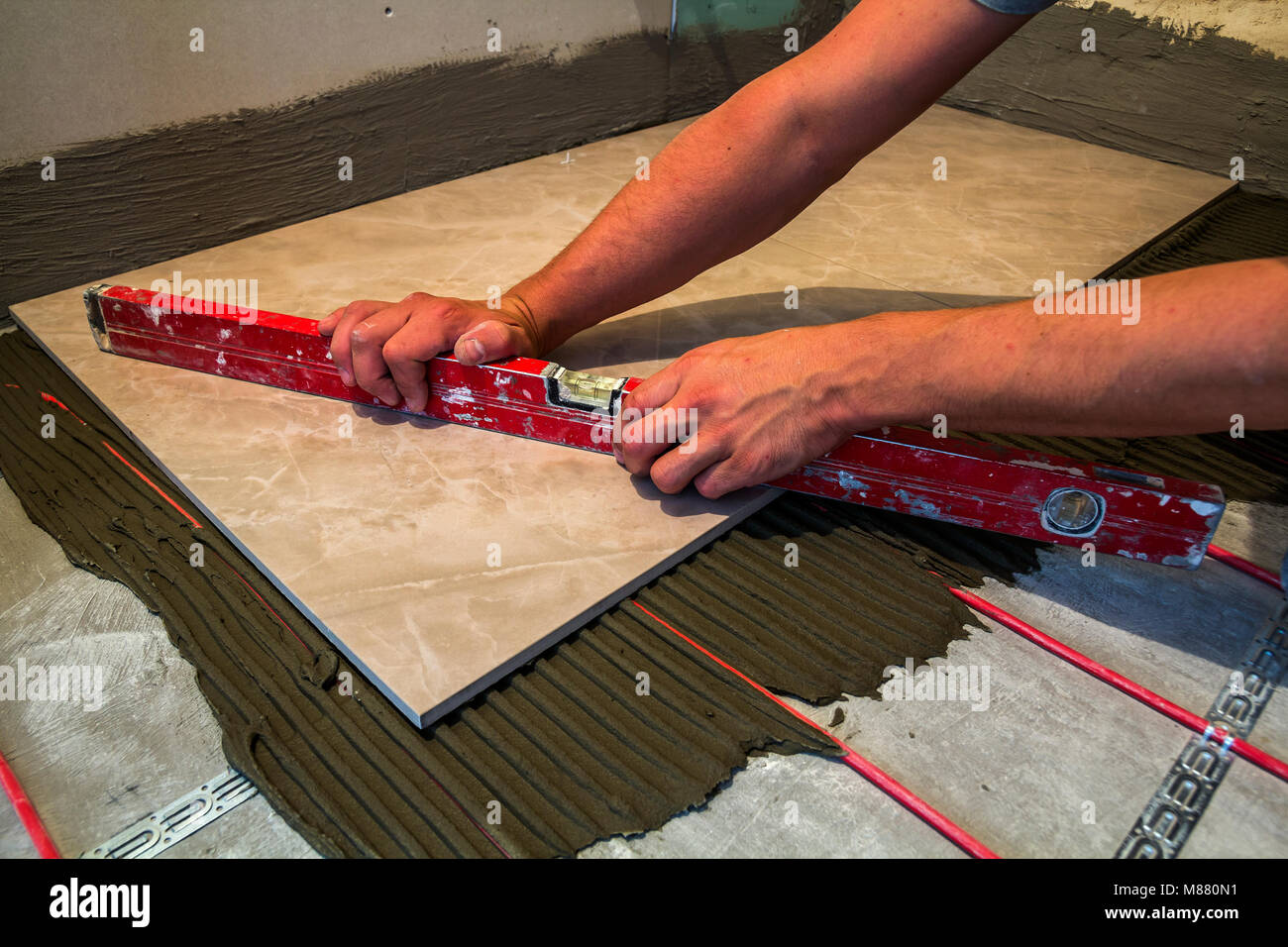 Ceramic tiles and tools for tiler. Worker hand installing floor tiles ...