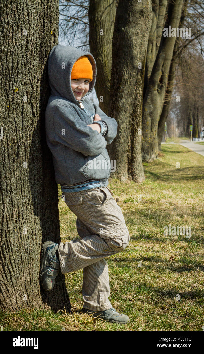 the boy is standing by the tree Stock Photo - Alamy