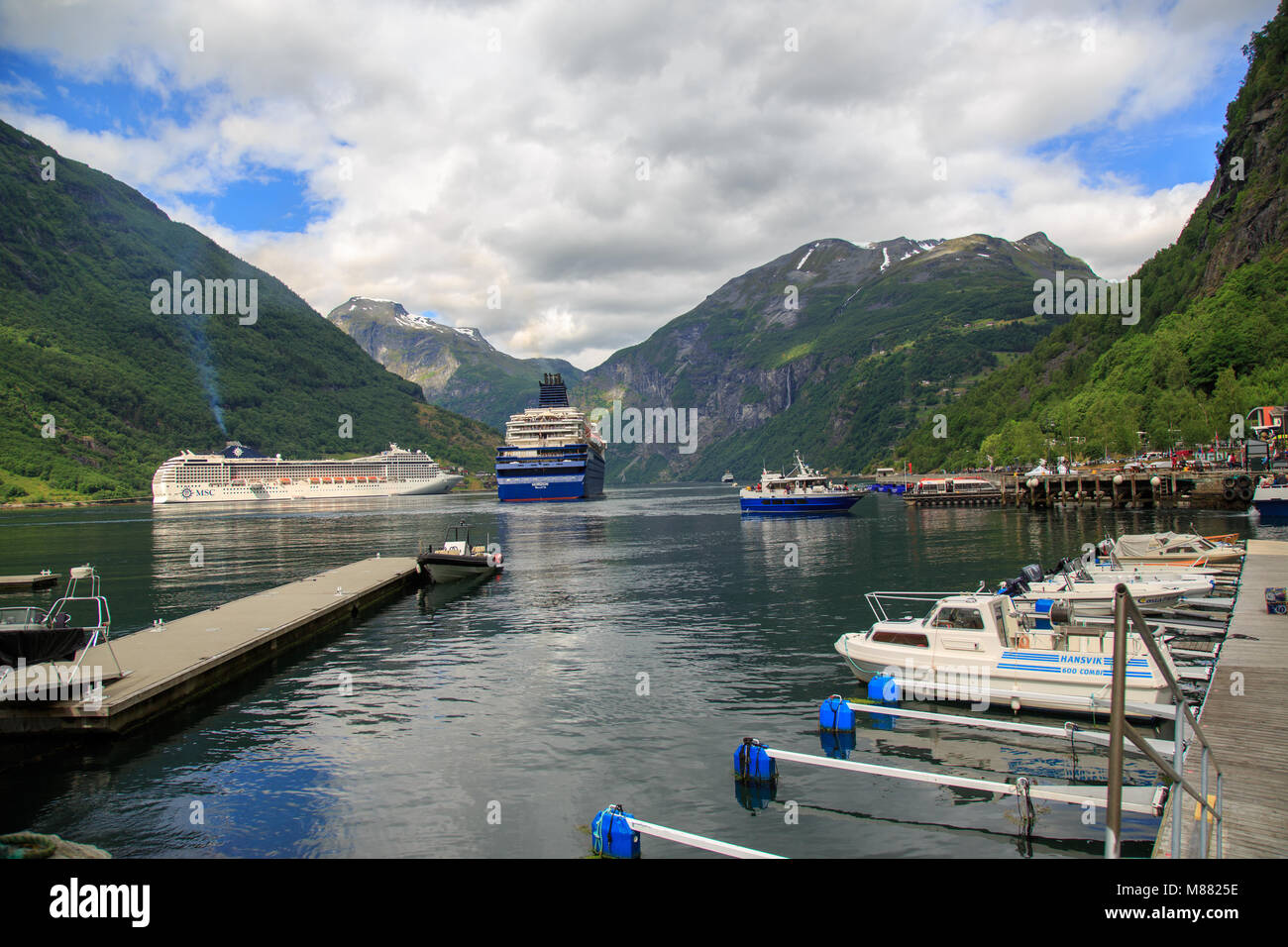 Cruise ships docking in Geiranger Harbour and the pier with small boats ...
