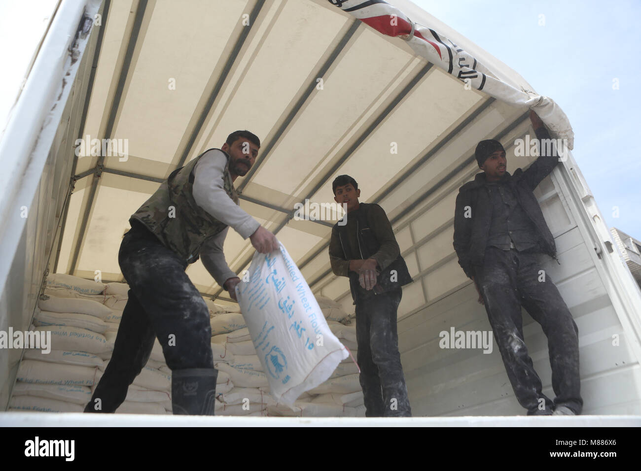 Syrians offload sacks of flour after a humanitarian convoy carrying ...