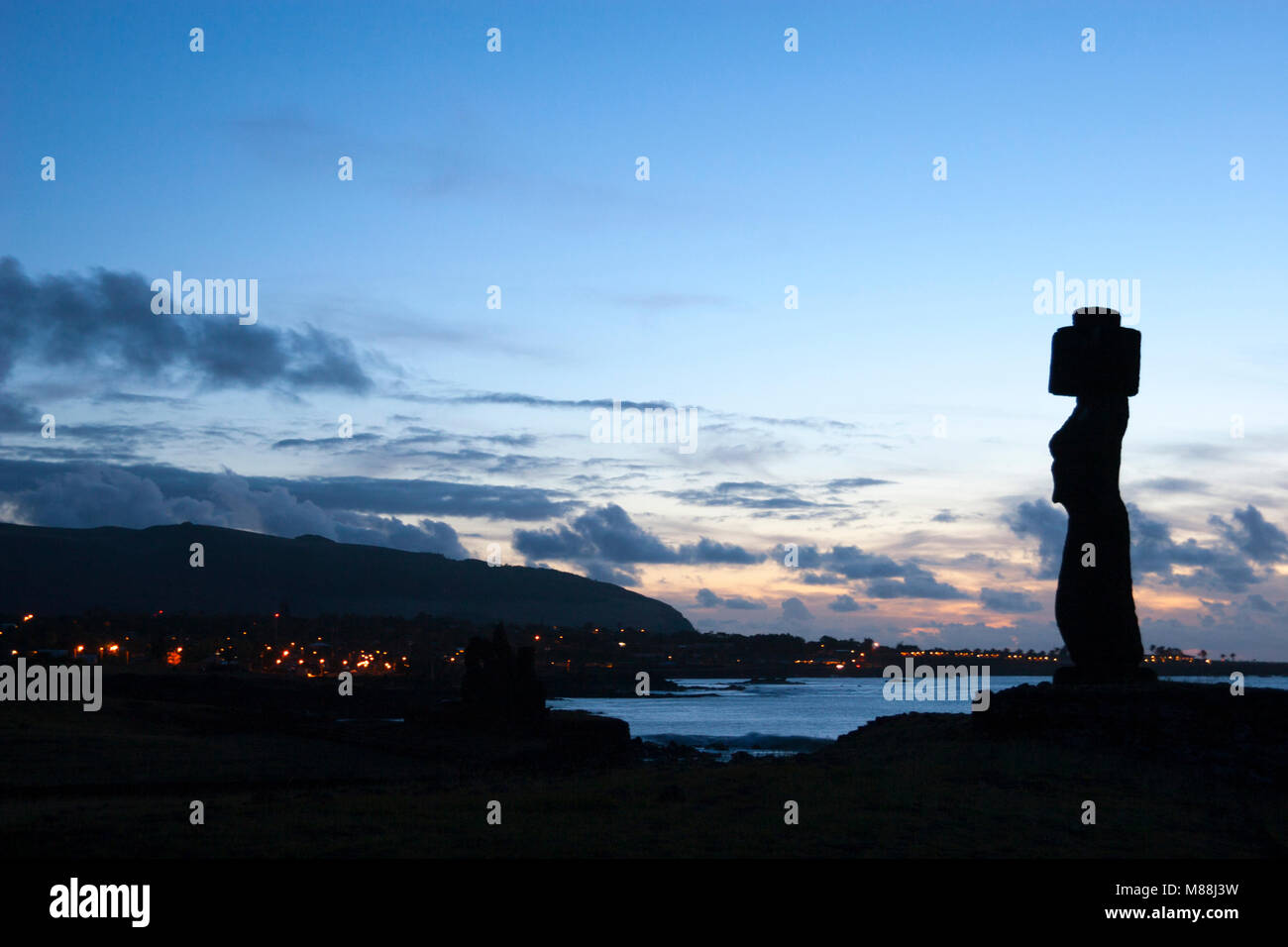 Ancient moai at Ahu Tahai overlooking night lights of modern Hanga Roa ...