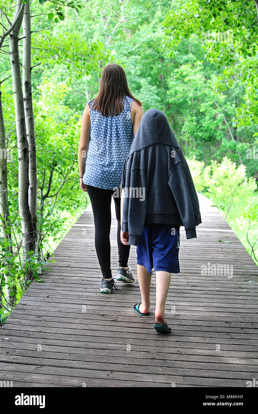 A young boy following a girl on a boardwalk on a tail Stock Photo - Alamy