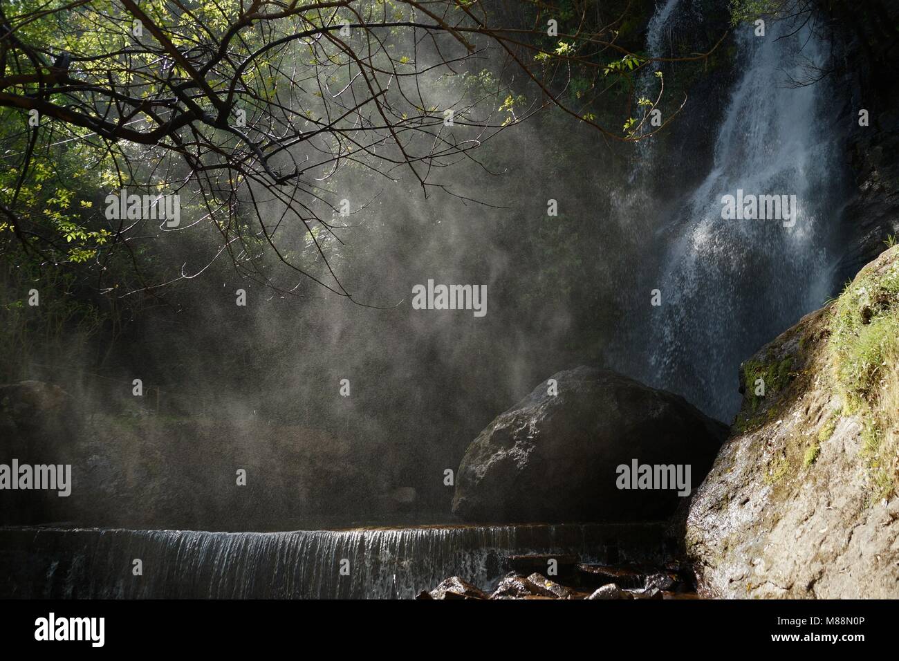 Waterfall and lower cascade in the forest with water fog lit with ...