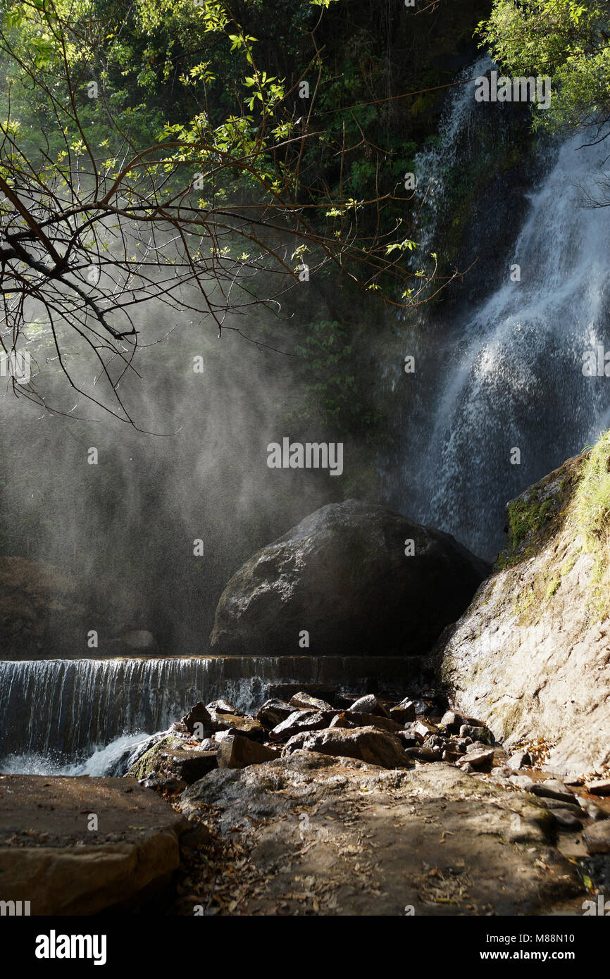 Waterfall and lower cascade in the forest with water fog lit with ...