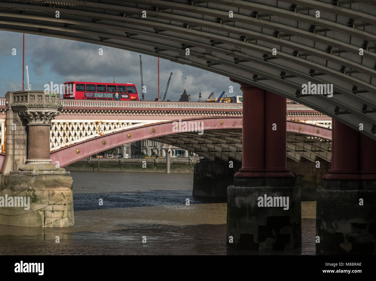 A London bus crosses Blackfriars Bridge as seen from under the arches ...