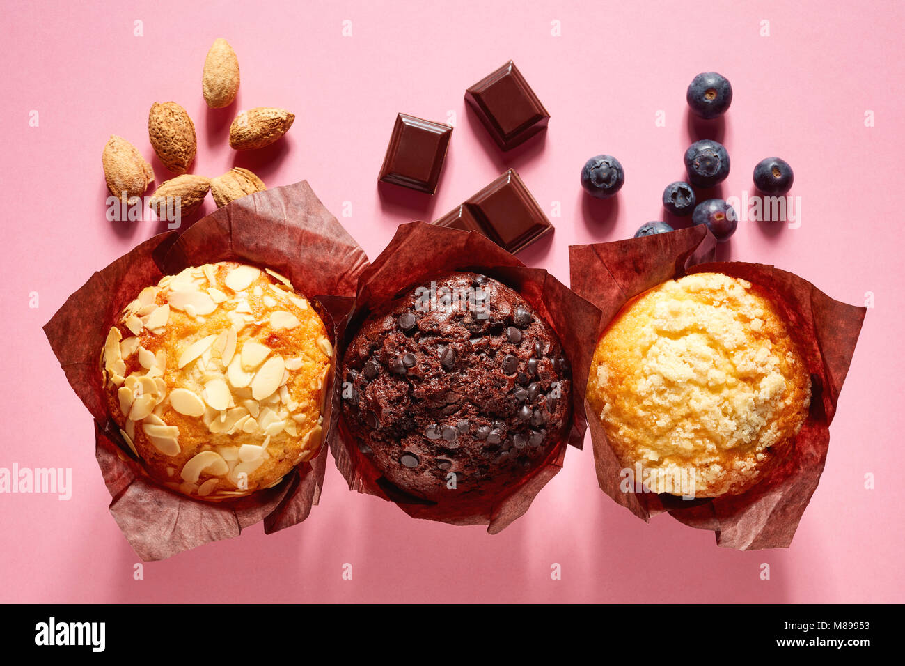 Assorted muffins in brown paper on pink background, top view Stock ...