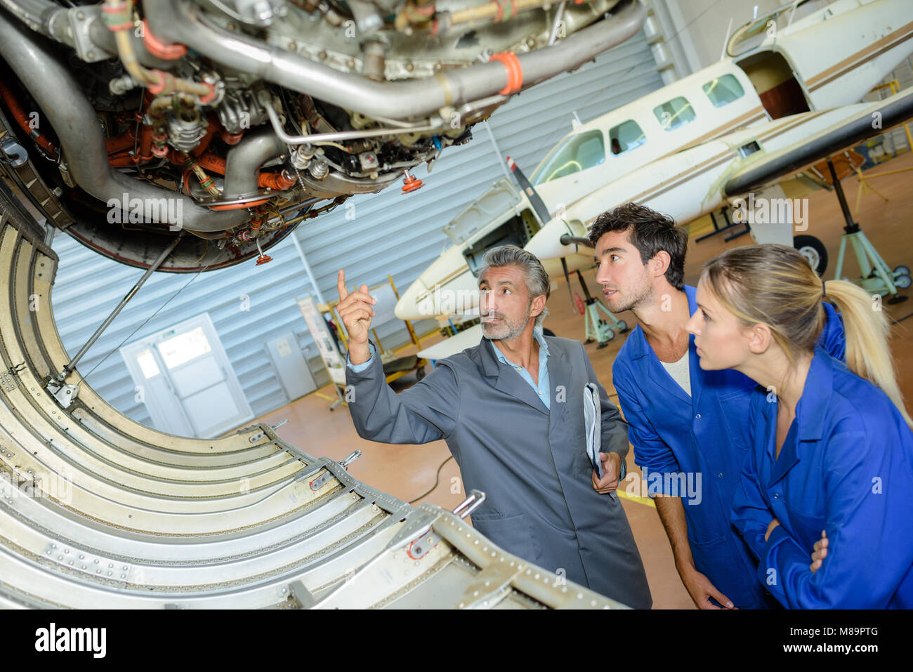 airplane engineer showing apprentices mechanics inside undercarriage ...