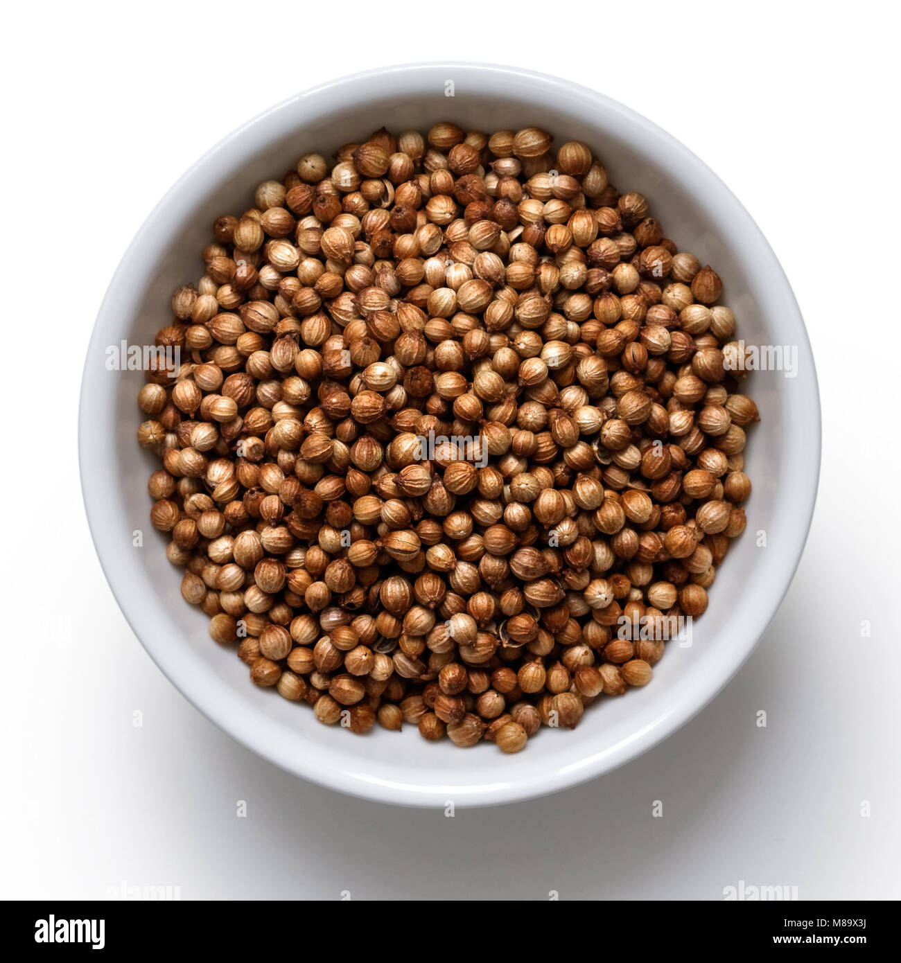 Whole dried coriander seeds in white ceramic bowl isolated on white from above Stock Photo - Alamy