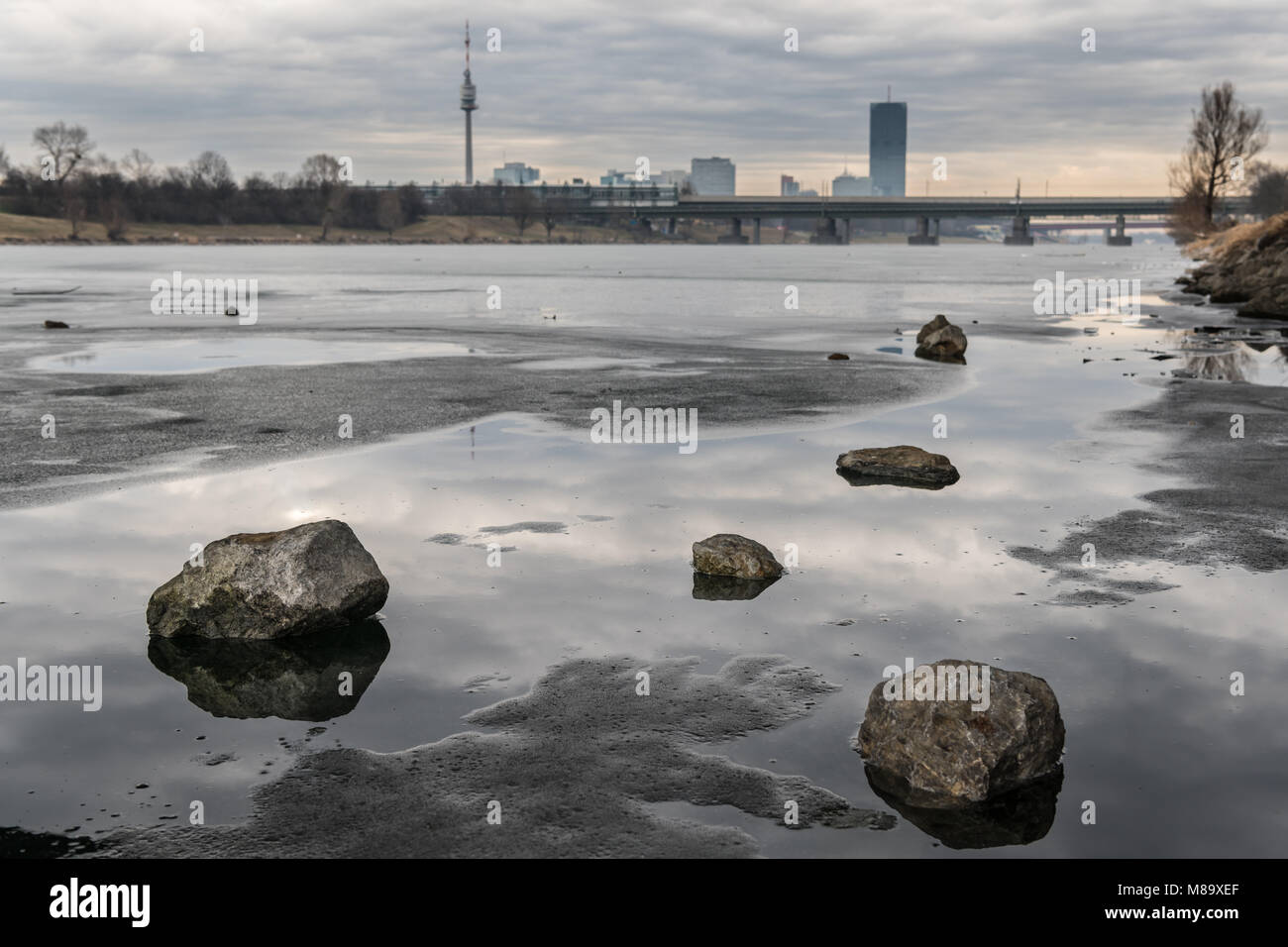 Frozen river, stones lying on the ice and high buildings in the ...