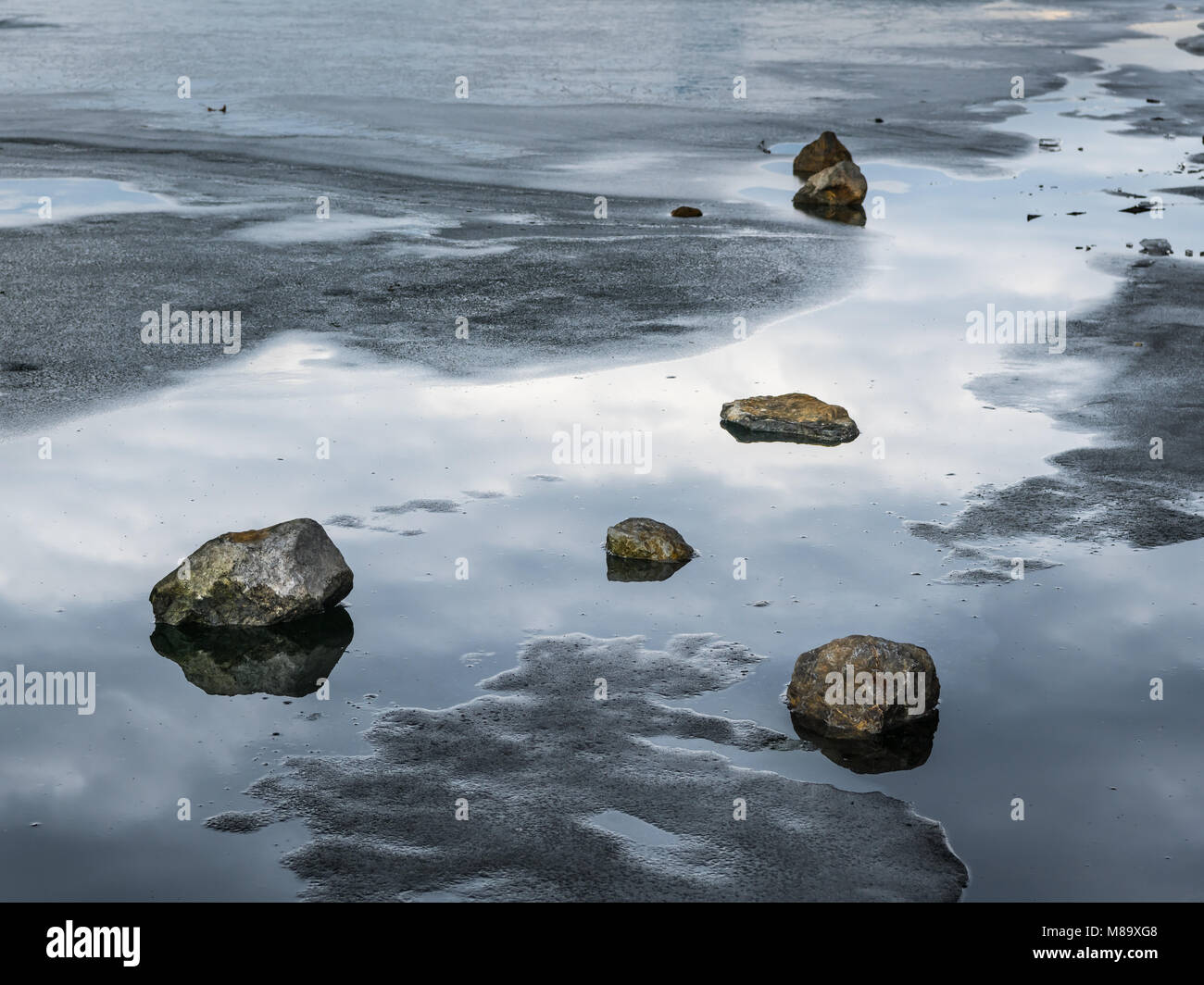 Stones lying on the melting ice of a frozen river, Neue Donau Vienna ...