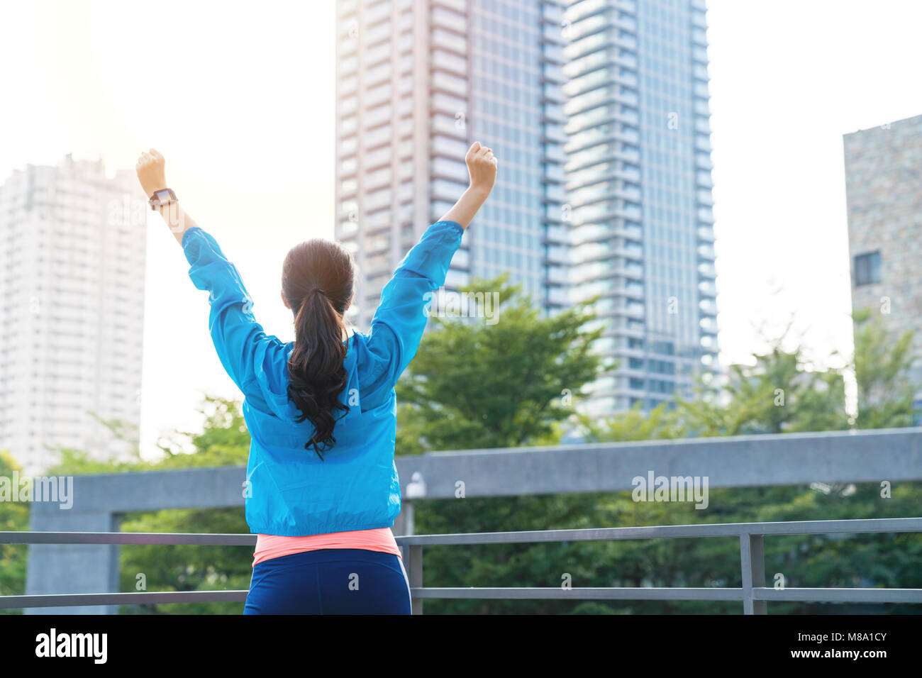 Back view of female athlete raising arms to the sky for celebrating ...