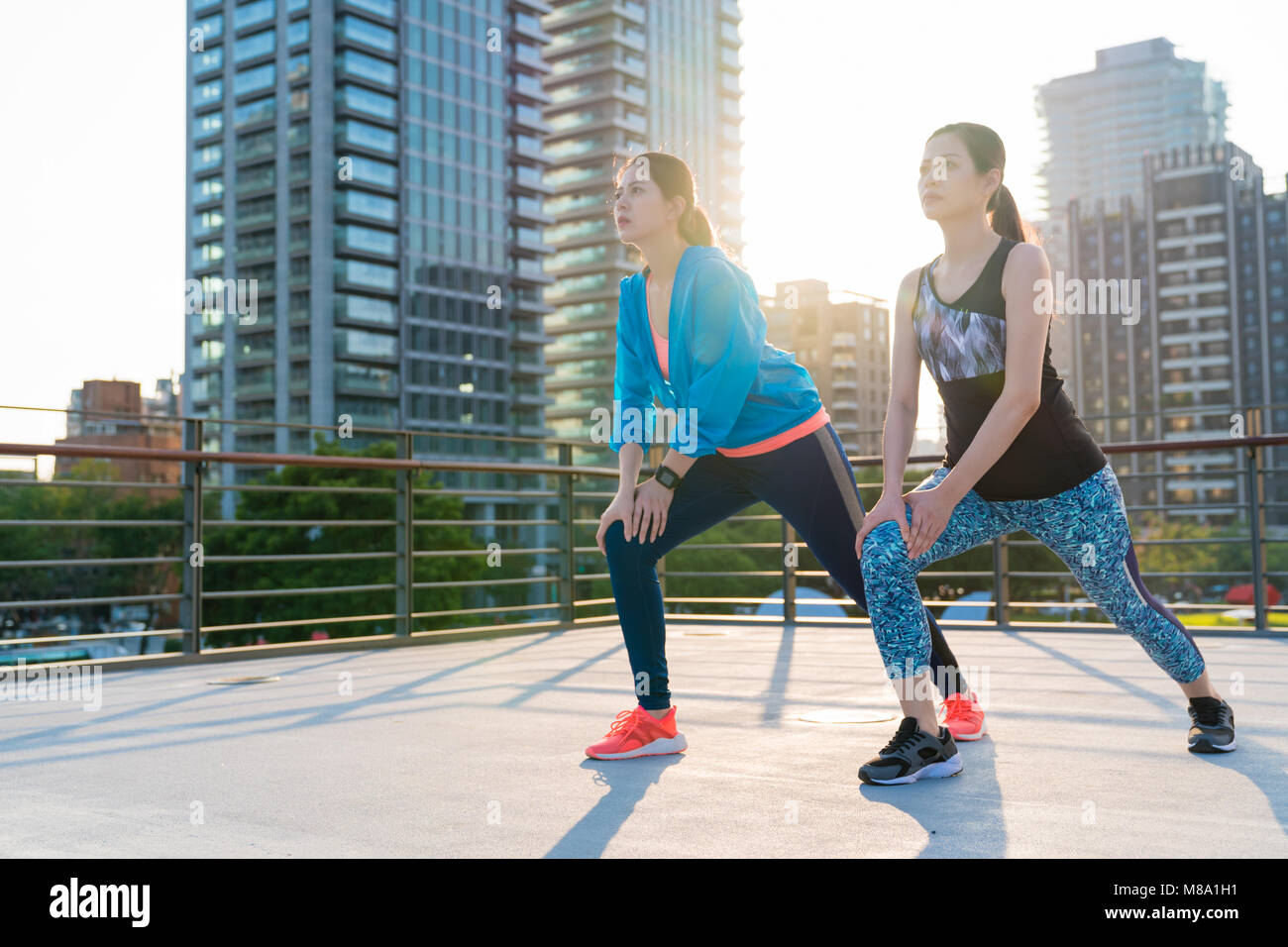 Female runners stretching legs after running training in sunshine at ...