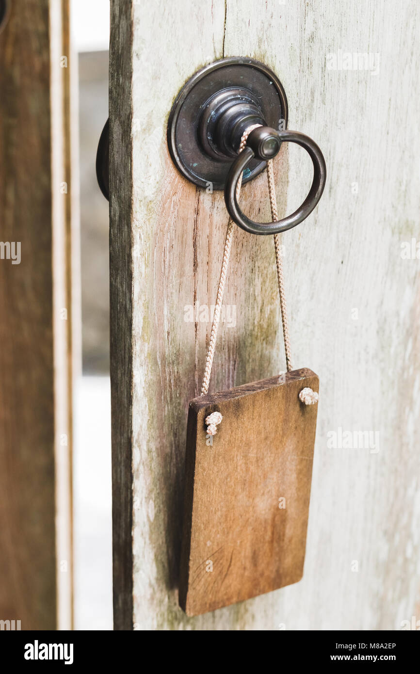Empty wooden plate hanging on metal door knob. Place for logo, text ...