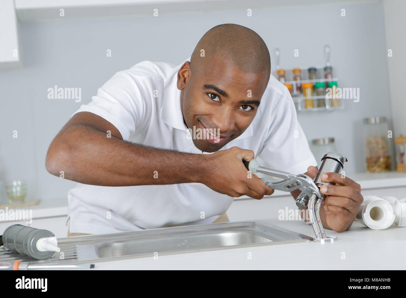 happy attractive young man fixing tap Stock Photo - Alamy