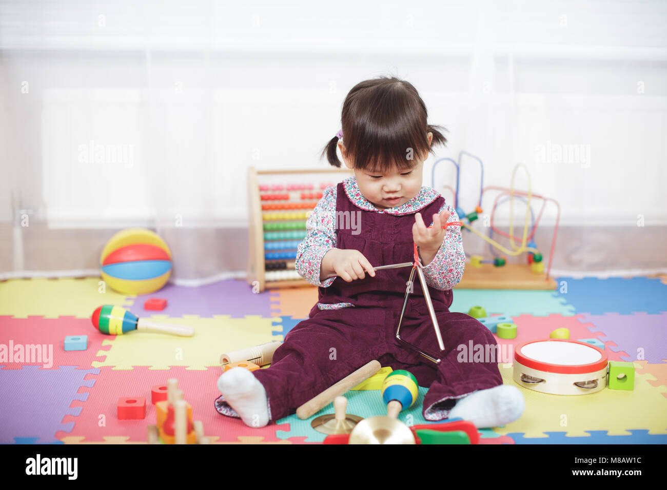 baby girl play triangle at home Stock Photo - Alamy