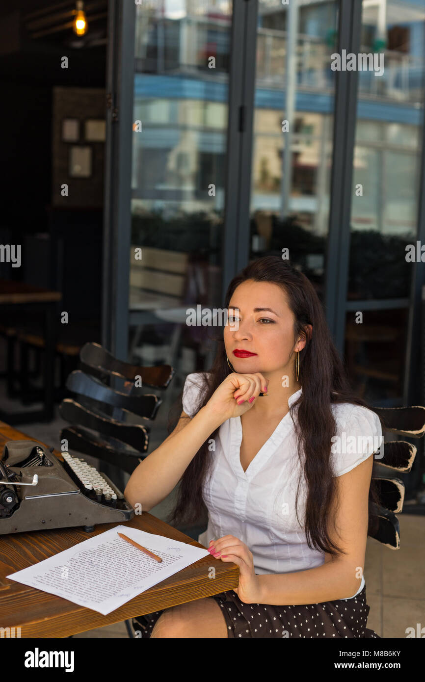 Female writer wearing white shirt and polka dot skirt working in an ...