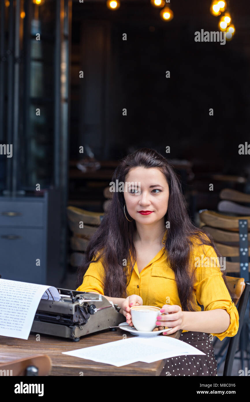 Beautiful female writer with long brown hair wearing yellow shirt and ...