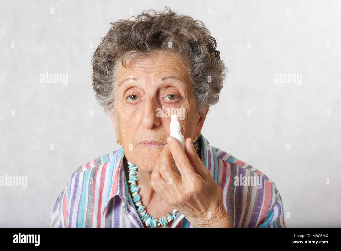 Senior woman between 70 and 80 years old and eye drops Stock Photo - Alamy