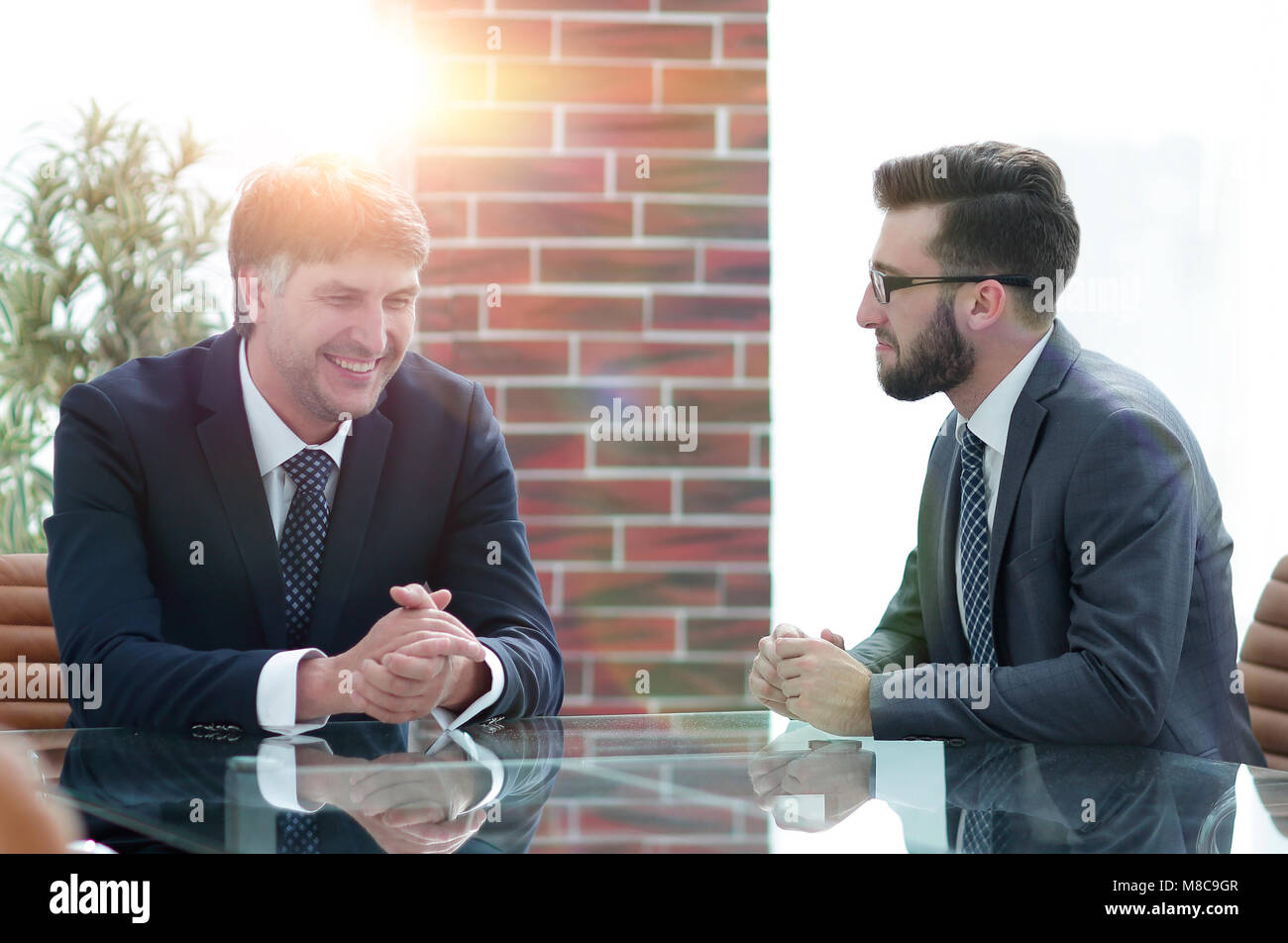 Two businessmen discussing tasks sitting at office table Stock Photo ...