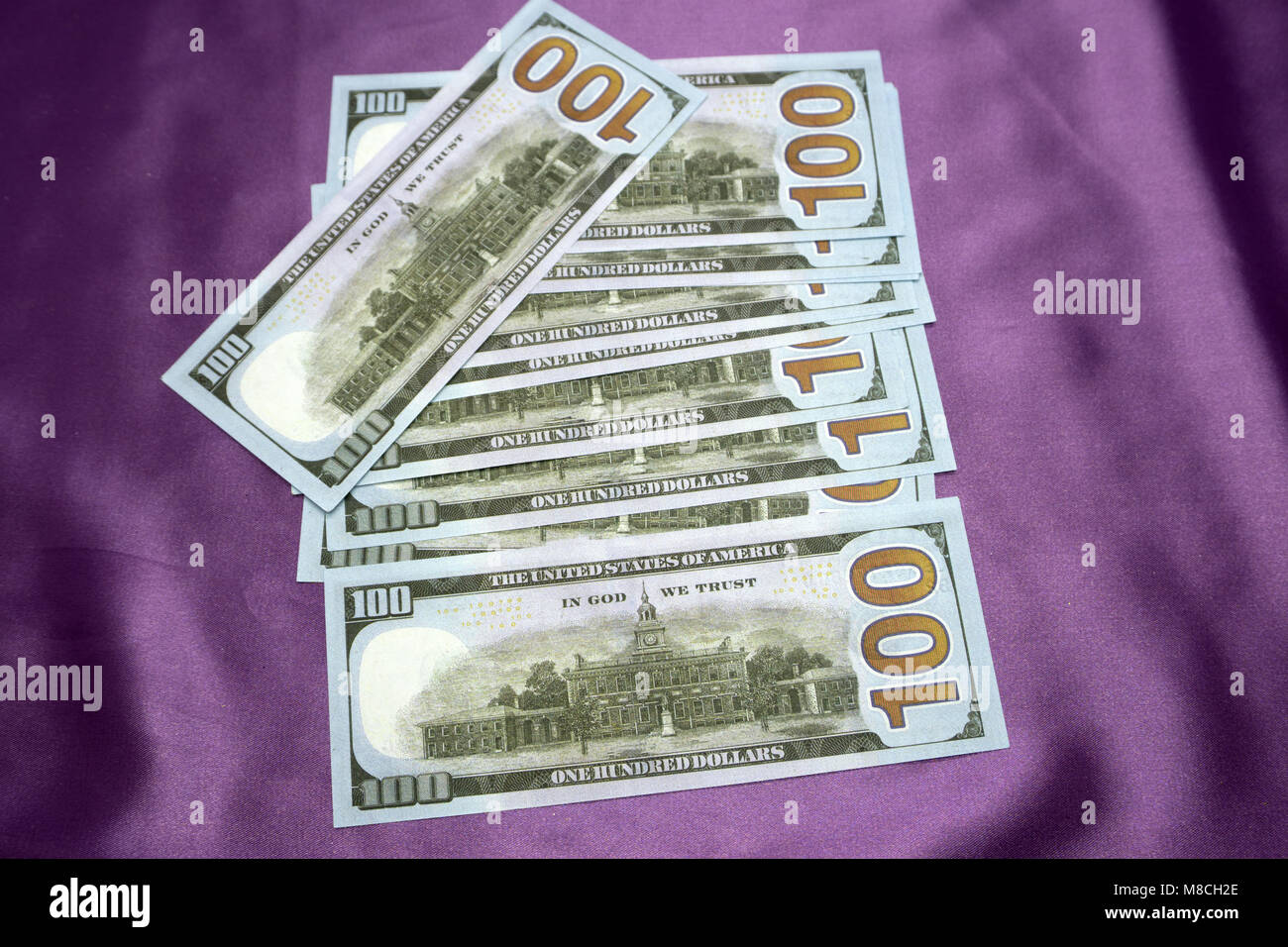 100 dollars banknotes on a purple background Stock Photo - Alamy